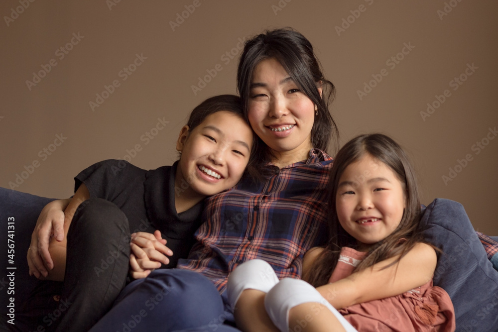 Happy asian family portrait of mom and two daughters on couch at home, moments together Stock ...