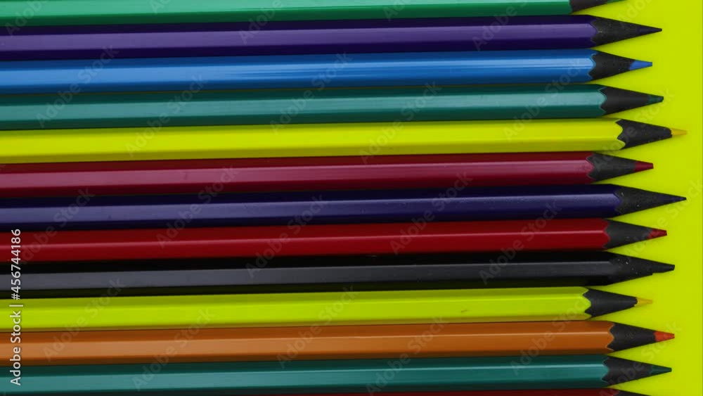 Colored pencils are moving against a yellow background. A row of ...