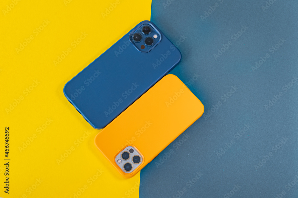 Modern mobile phones in blue and yellow leather cases on a bright ...