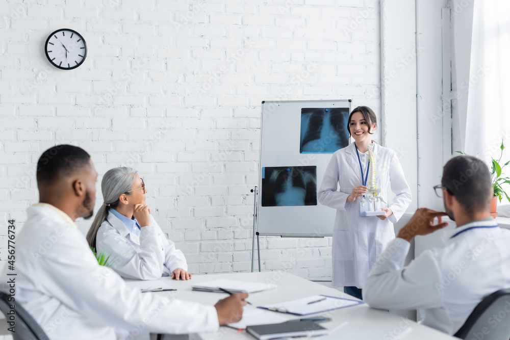 smiling doctor standing near flip chart with lungs x-rays and showing ...