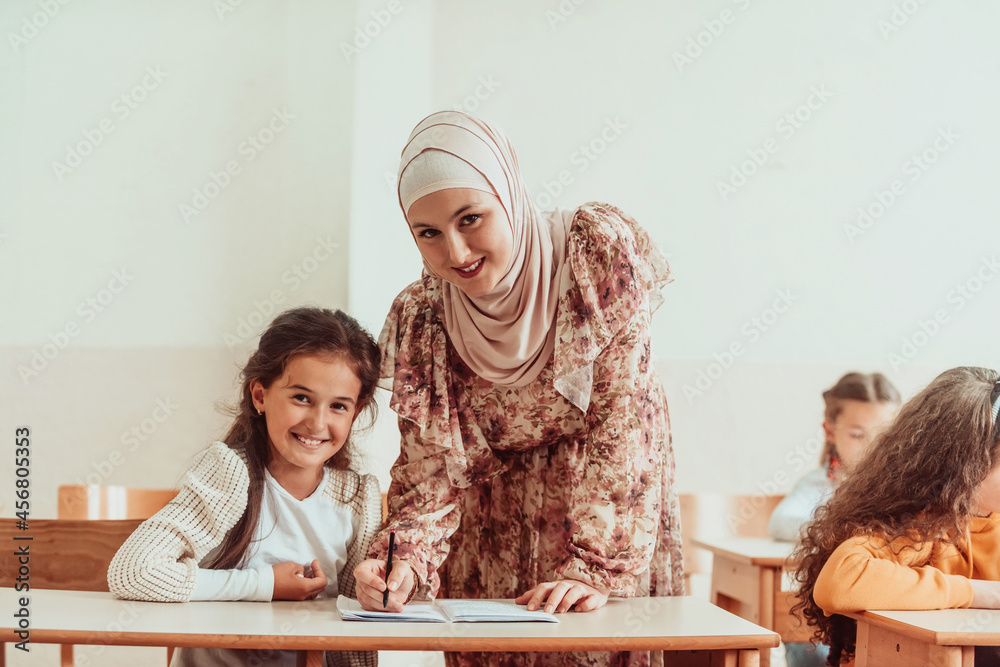 Female hijab muslim teacher helps school kids to finish they lesson ...