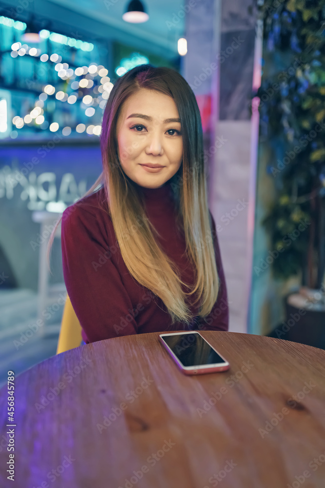Cute asian woman sitting at table with mobile phone in cafe. Beautiful ...