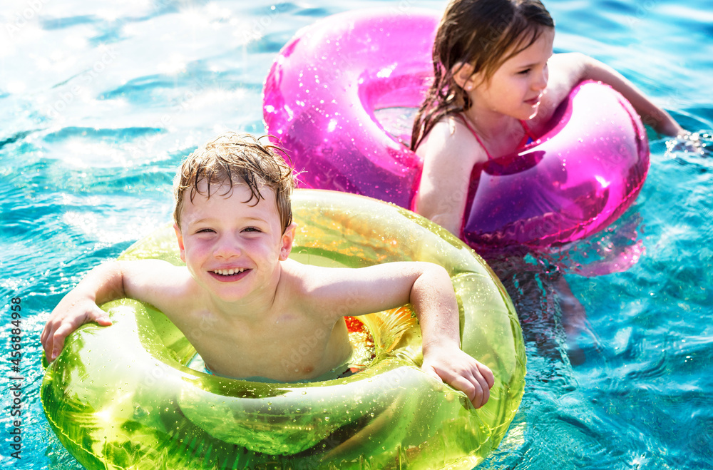 Cheerful brother and sister swimming in the pool Stock Photo | Adobe Stock