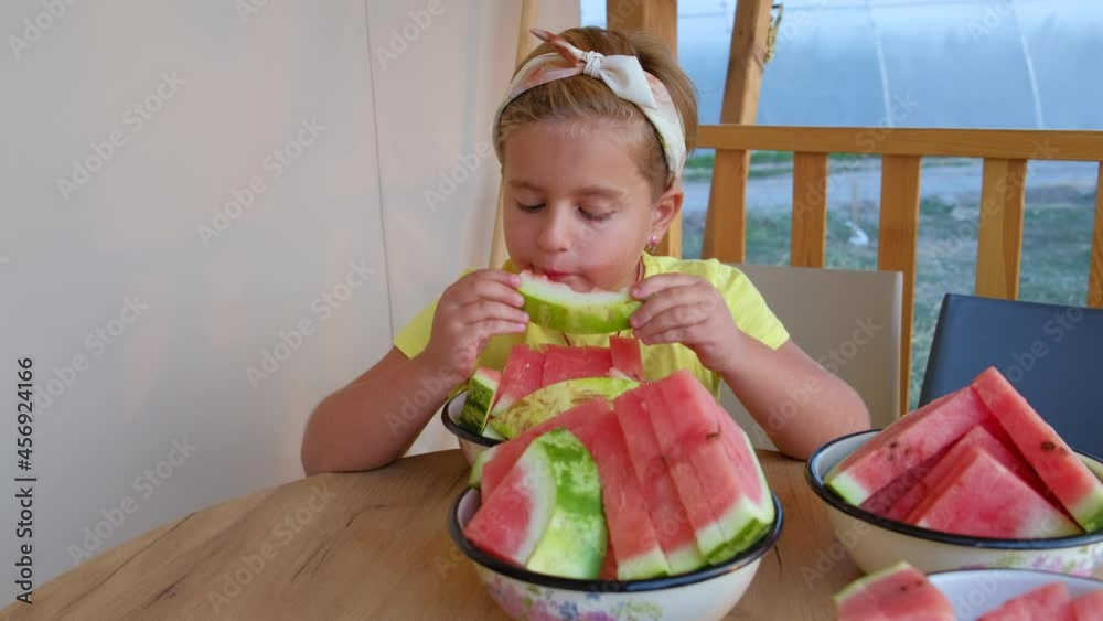 Child girl eating watermelon at the glamping table. Lots of watermelon ...