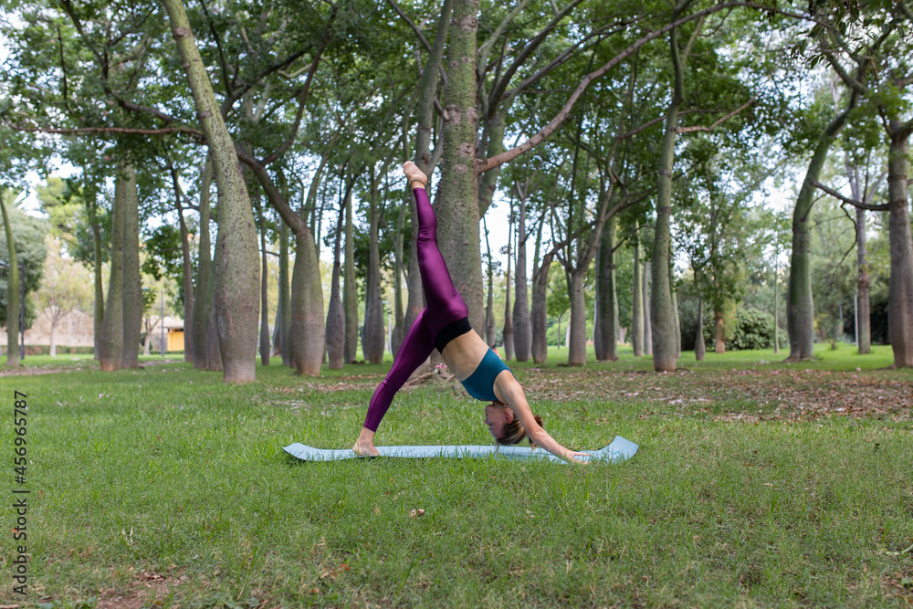 Slim female doing side plank star pose during yoga session in park ...