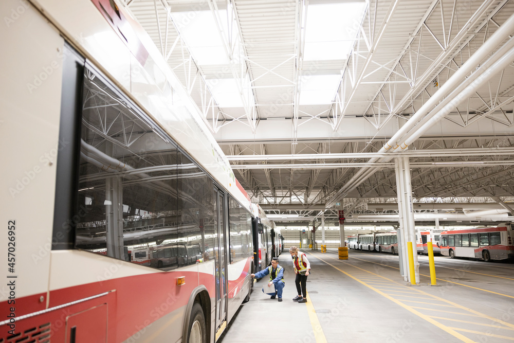 Engineers inspecting bus in transit garage Stock Photo | Adobe Stock