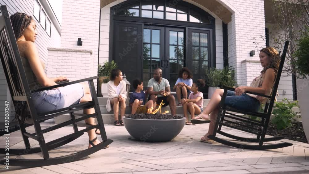 Family relaxing around fire pit on summer patio Stock Video | Adobe Stock