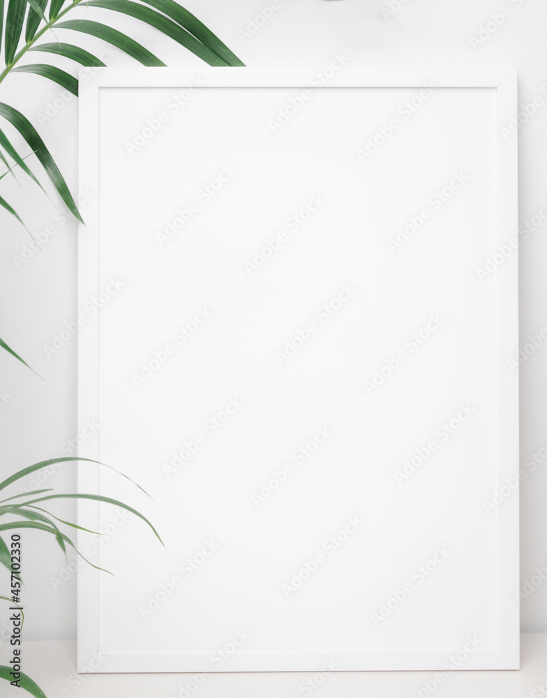 White poster frame decpration with green palm leaf over white wall ...