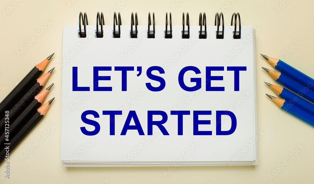 On a light background, a white notebook with the text LET IS GET ...