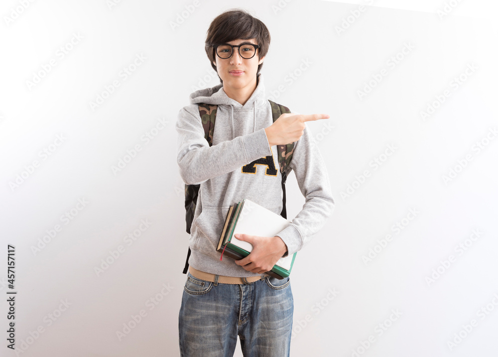 Handsome teen boy students carrying a backpack and books pointing ...