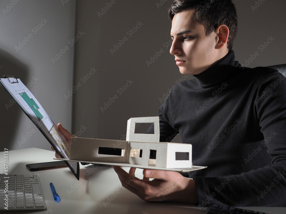 Architectural drawing in hands of a man. He made a layout of house in ...