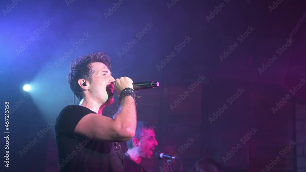 Enthusiastic male rock musician singing into microphone on nightclub ...