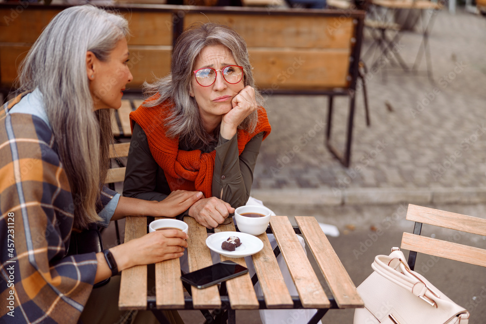 Mature Asian lady cheers up upset long hoary haired friend sitting ...