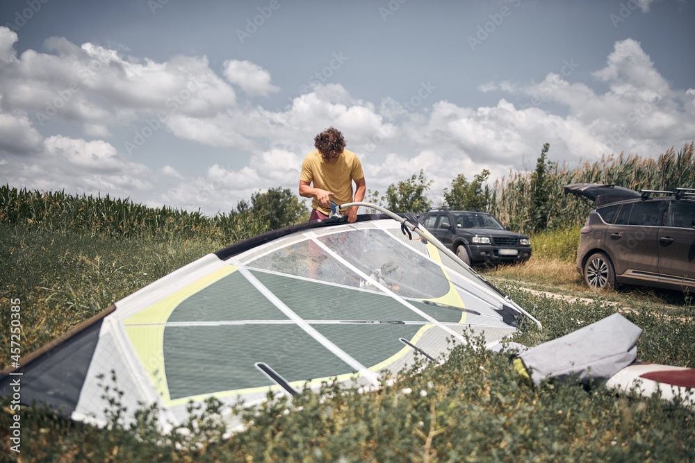 Windsurfer and camper packing and unpacking from a car's roof rack in ...