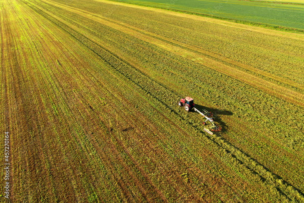 Tractor raking grass for silage harvesting. Agriculture machinery ...