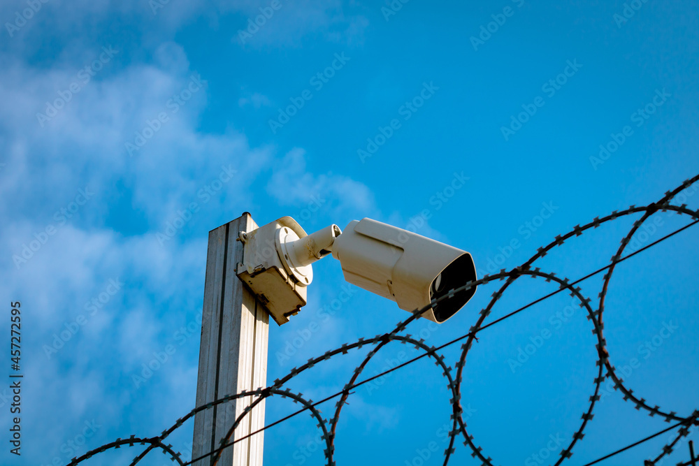 A security camera or CCTV camera with barbed wire fence. Security ...