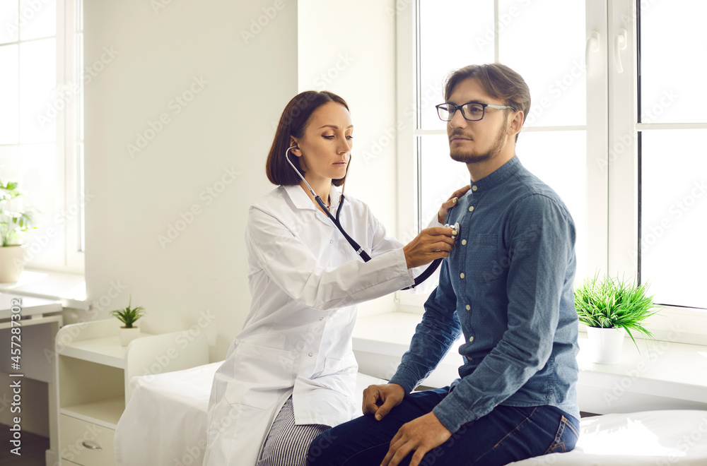 Young man visiting doctor for health exam. Serious middle aged female ...