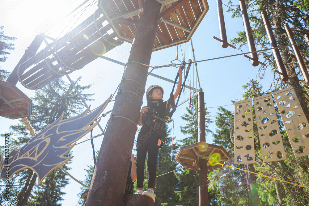 Little girl in safety equipment at adventure amusement park. Child ...