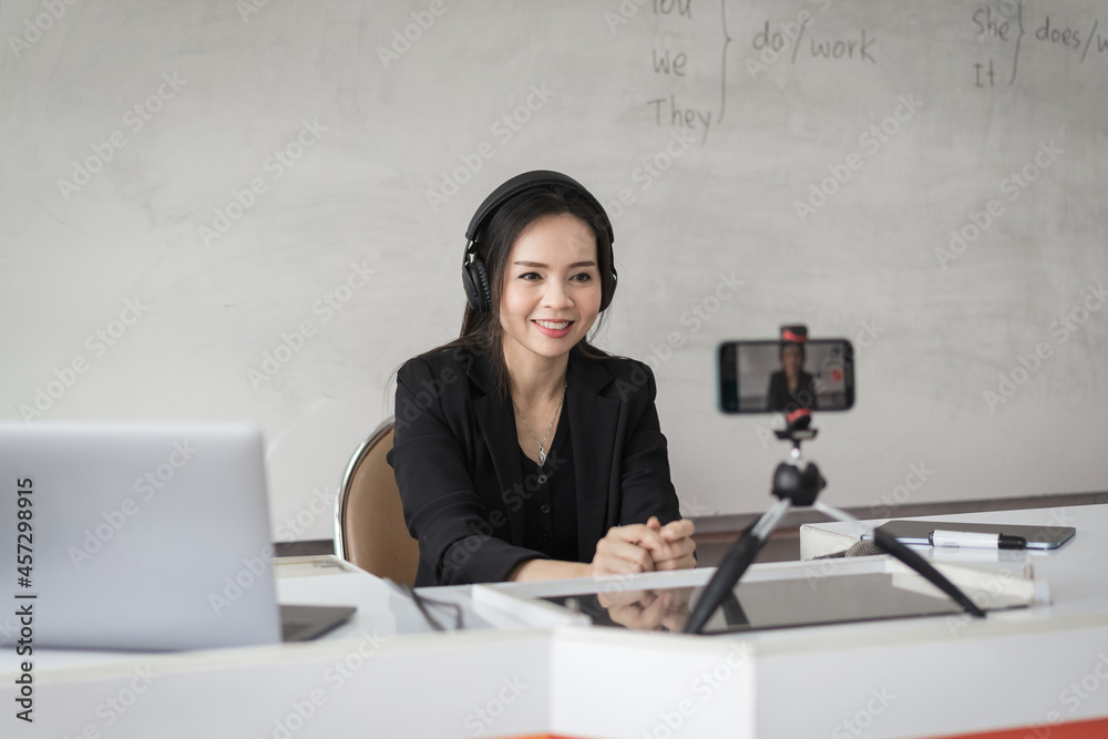 Adult Asian female college teacher teaching online via video conference ...