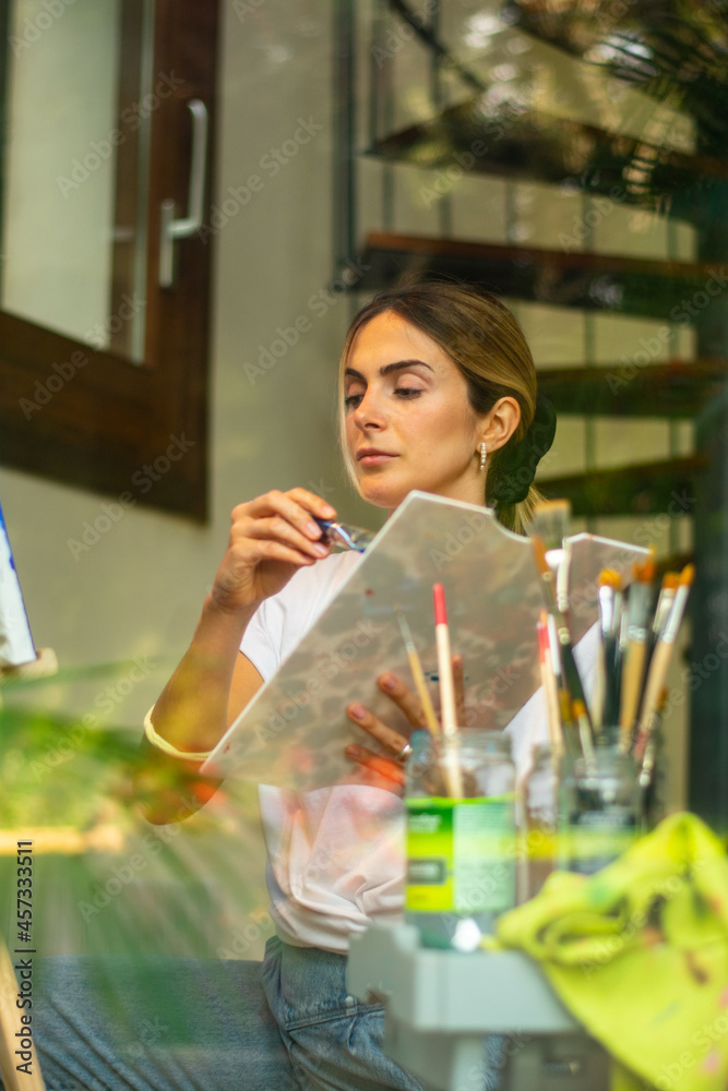 young blonde girl taking paint fromthe color palette on virtual class ...