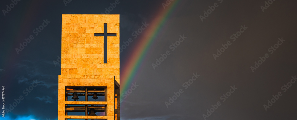 A rainbow above a modern church tower with christian cross, image with ...