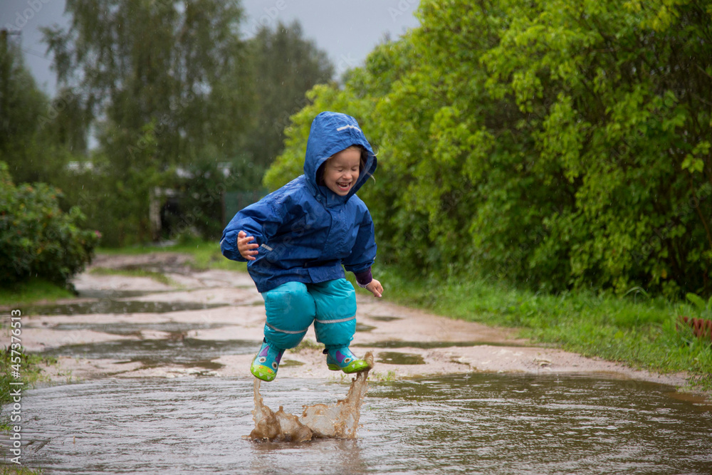Girl jumping in a puddle on a summer day. Stock Photo | Adobe Stock