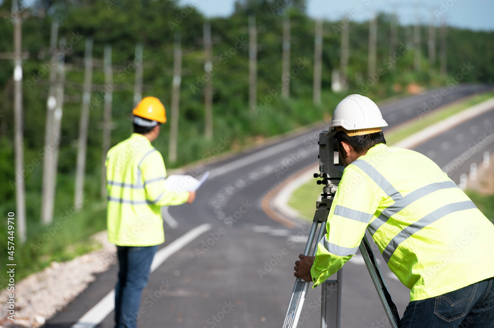 Road construction workers use orthogonal surveyors to measure angles in ...