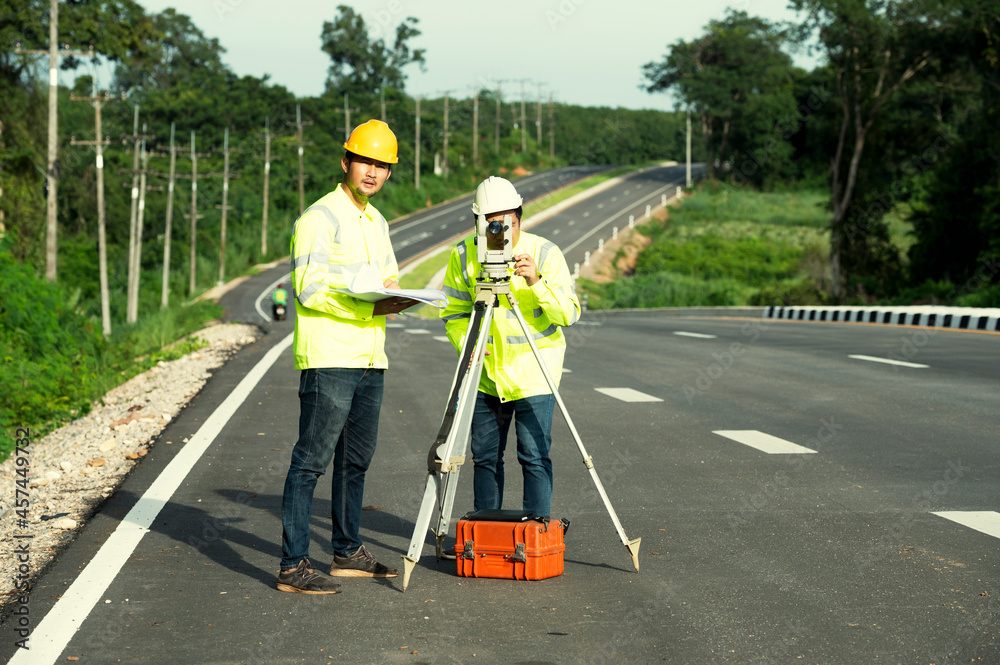 Road construction workers use orthogonal surveyors to measure angles in ...