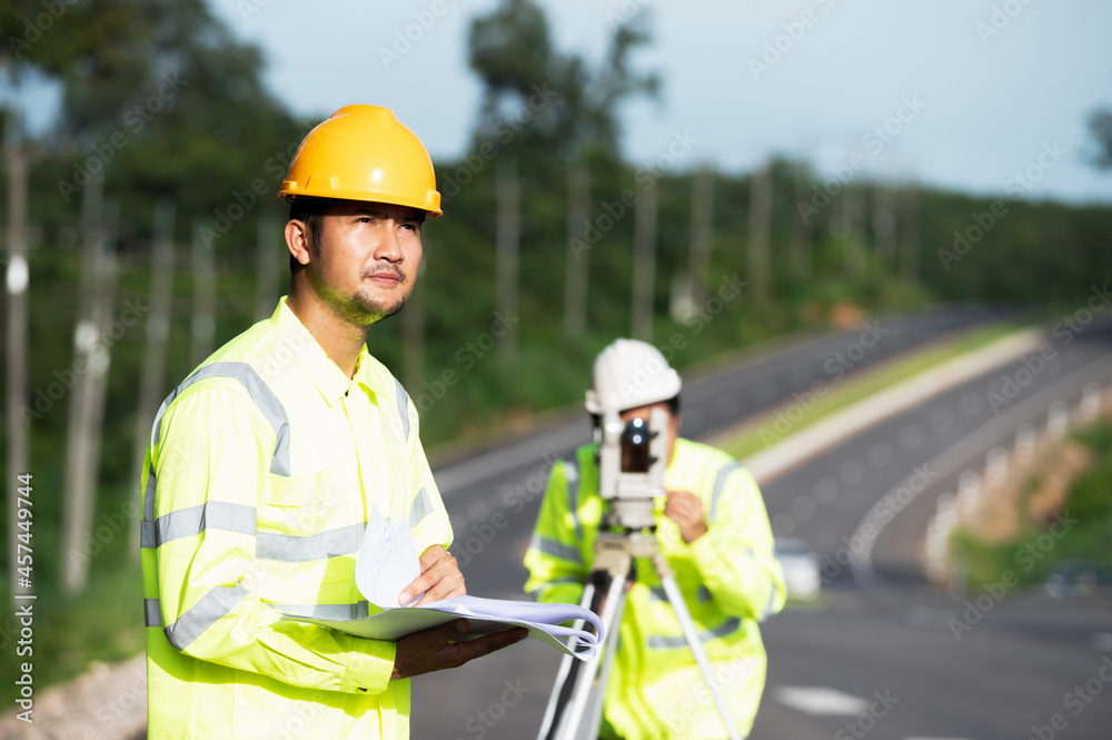 Road construction workers use orthogonal surveyors to measure angles in ...