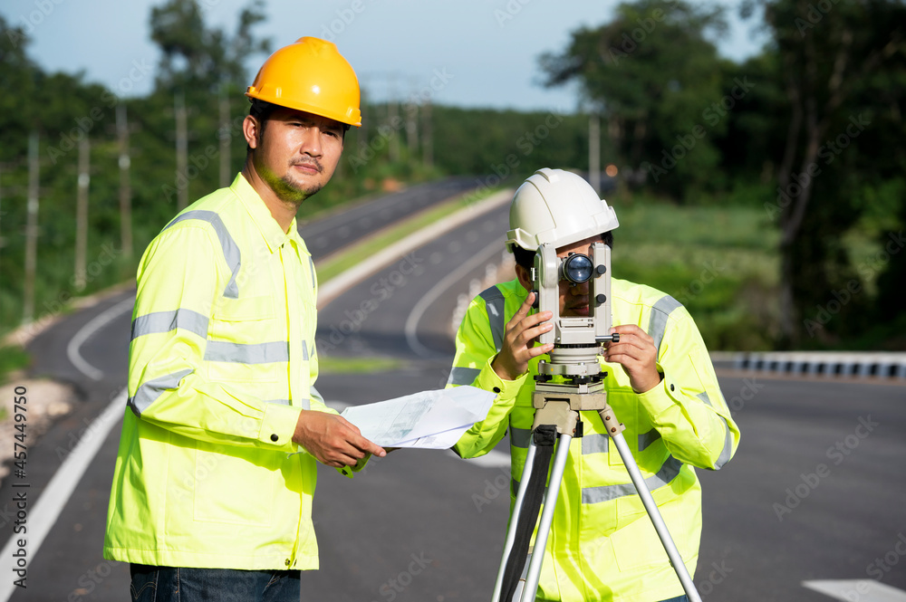 Road construction workers use orthogonal surveyors to measure angles in ...