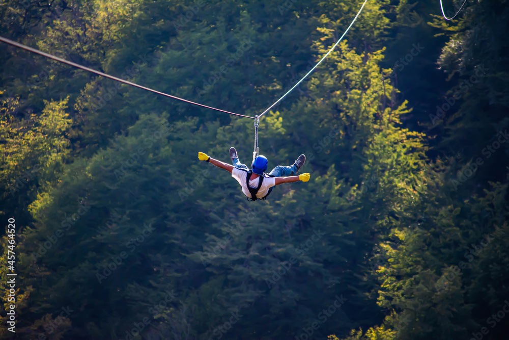 Fun, adrenaline and adventure on the zip line. Teenager having fun on a ...