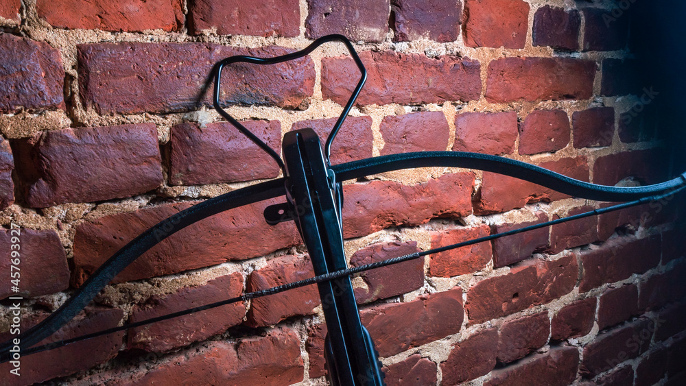 A modern compound crossbow handgun on the red brick wall background ...
