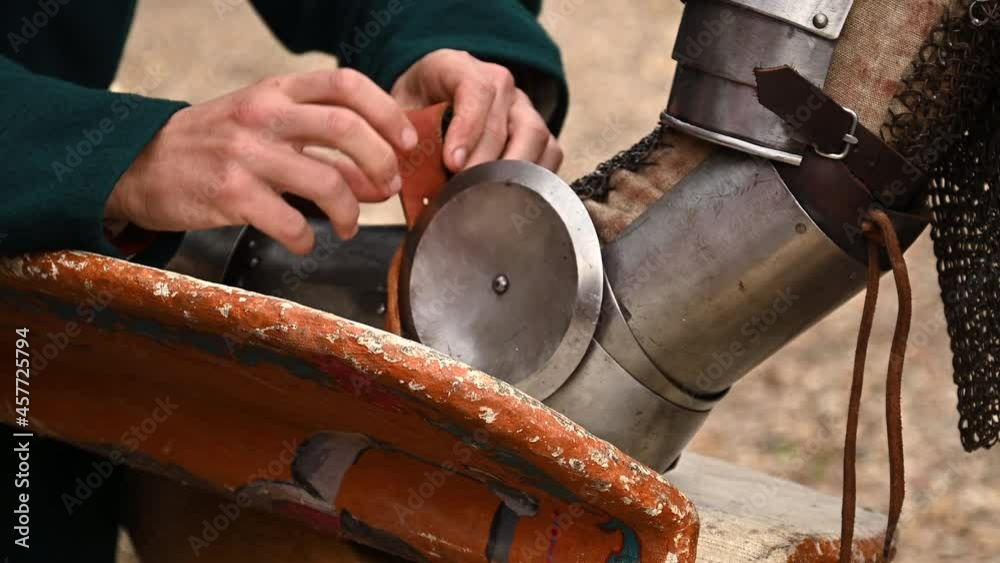 Squires help the knight to attach the shield to the armor on his arm ...