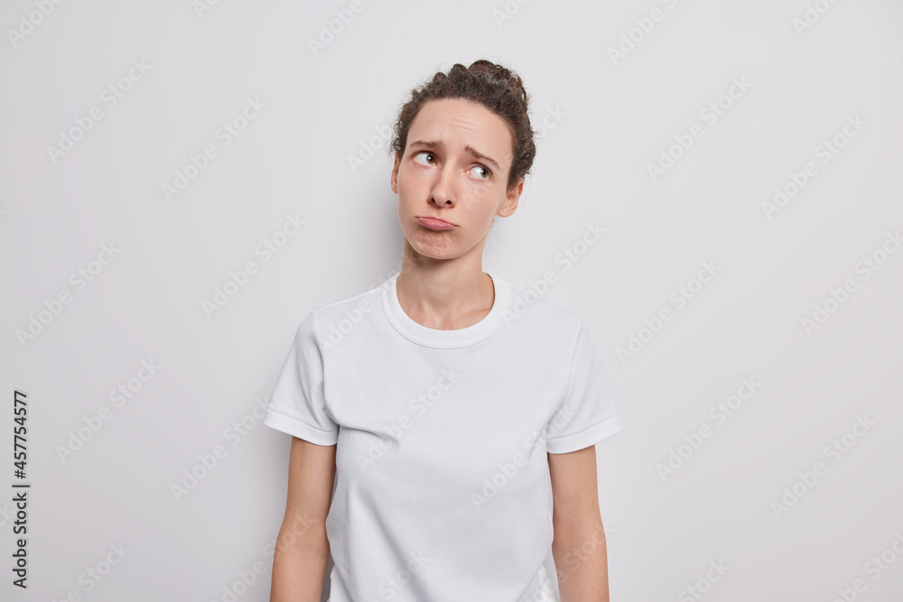 Depressed young sad European woman purses lips has gloomy face ...