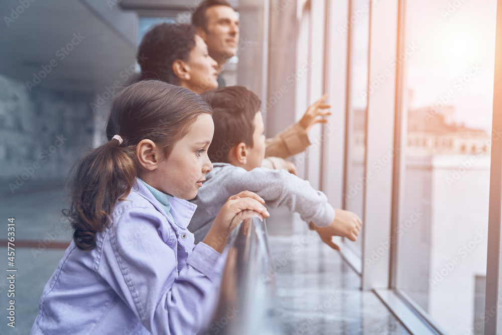 Family with two little kids looking through a window while waiting for ...