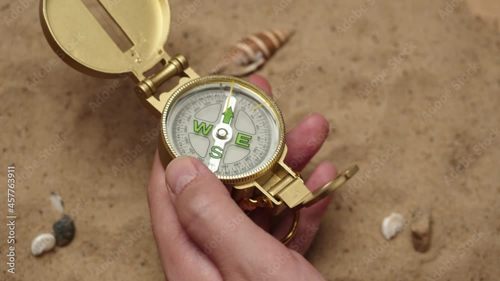 Man hand holding gold compass on sand background close-up, golden ...
