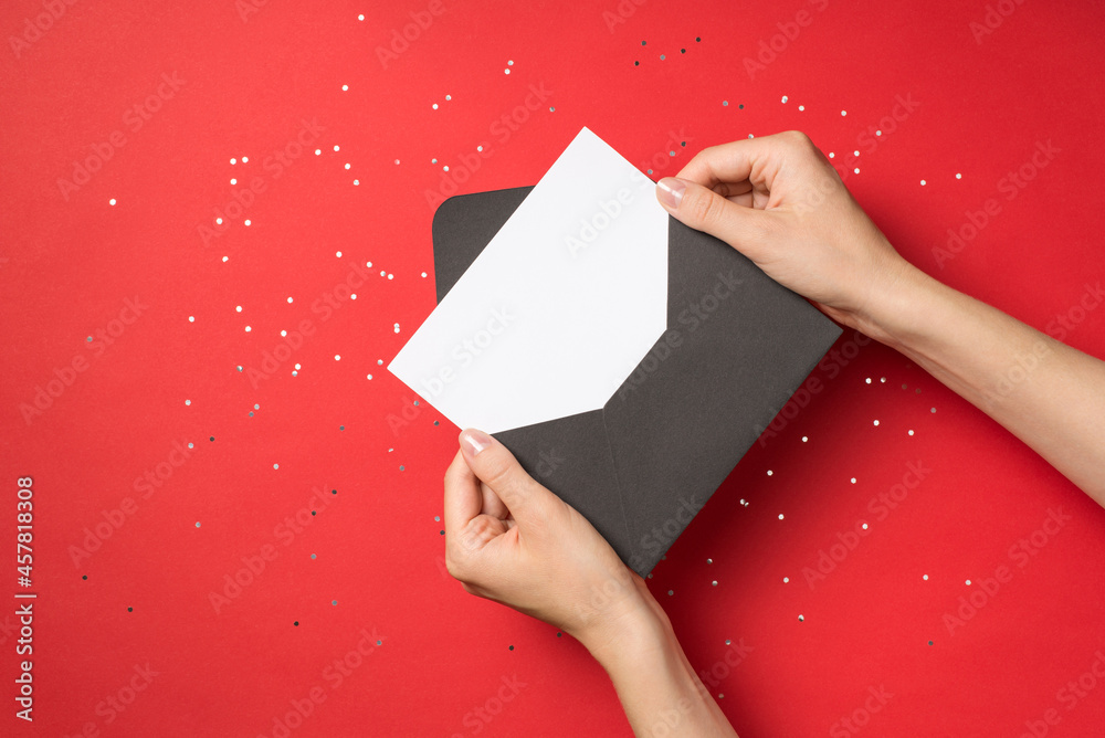 First person top view photo of hands holding open black envelope with ...