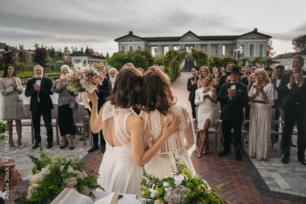 Portrait of two LGBT females lesbians brides posing during wedding ...