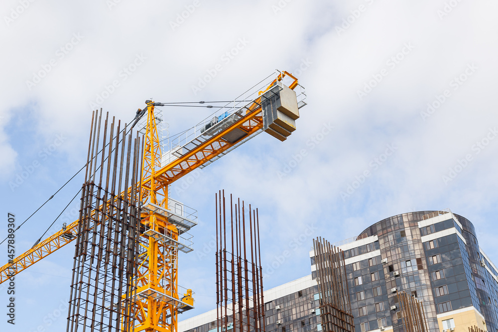 yellow tower crane at a construction site stands behind the ...