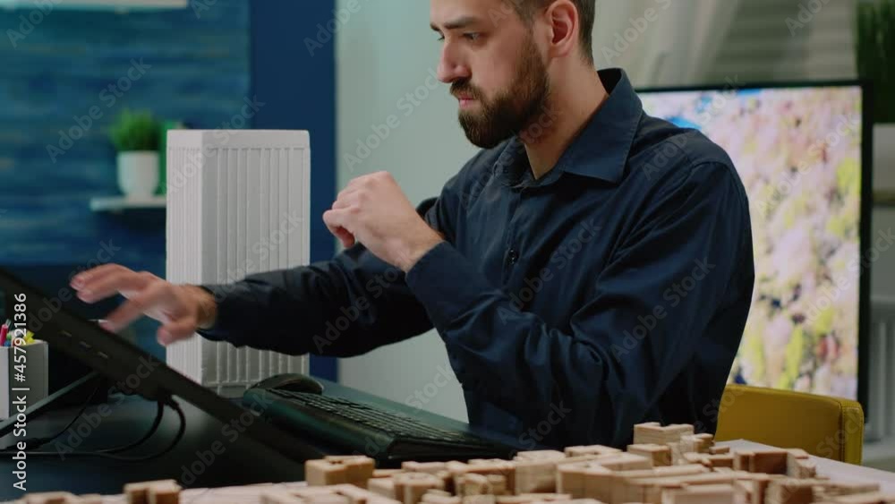 Close up of man working on computer with building model and maquette ...