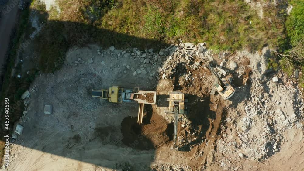 An aerial view of the excavator loading stones into the rock crusher ...