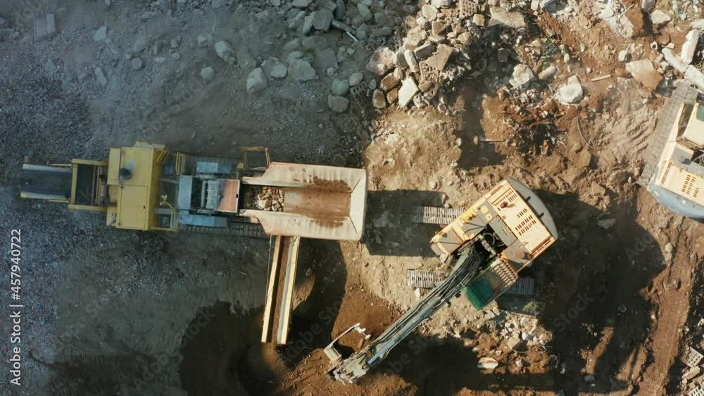 An aerial view of the excavator loading stones into the rock crusher ...