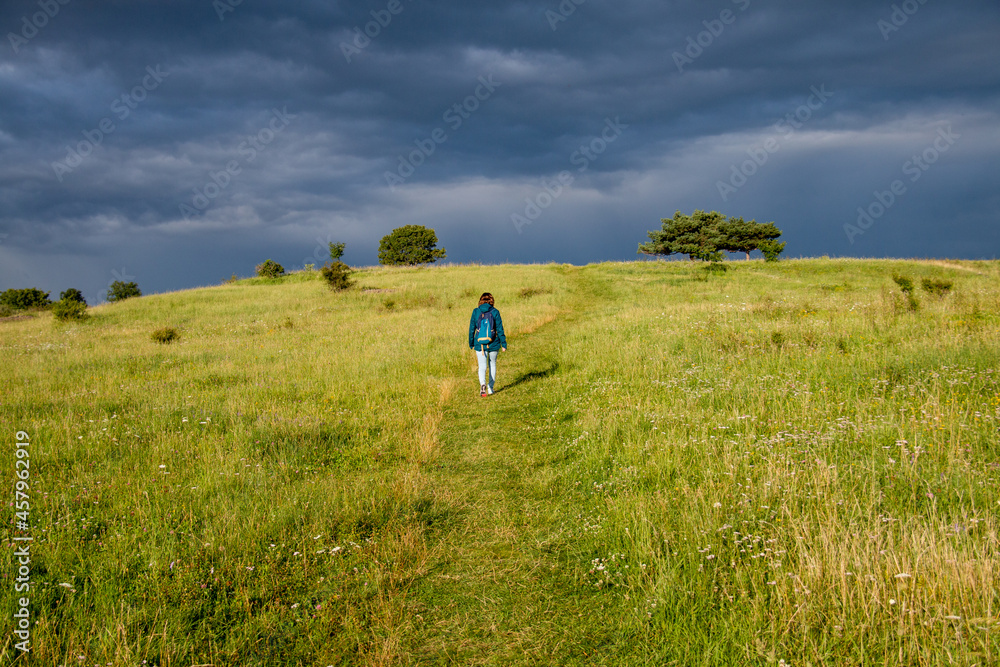 Marcheuse en randonnée au milieux d'un champs par un temps orageux ...