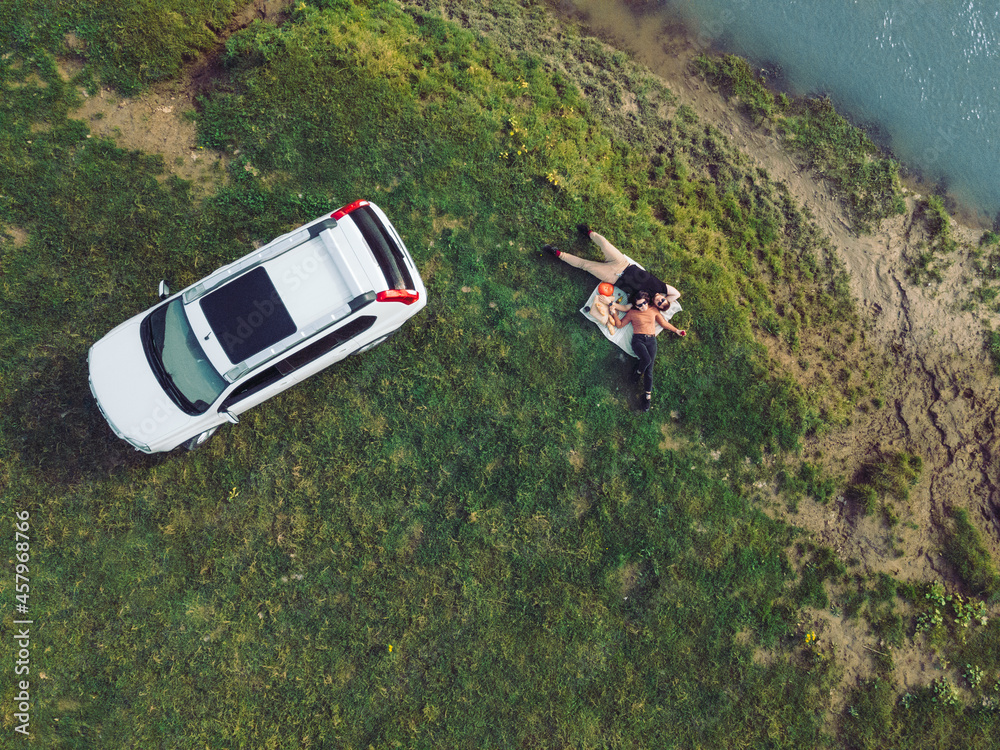 overhead top view of suv car and couple laying down on a blanket at ...