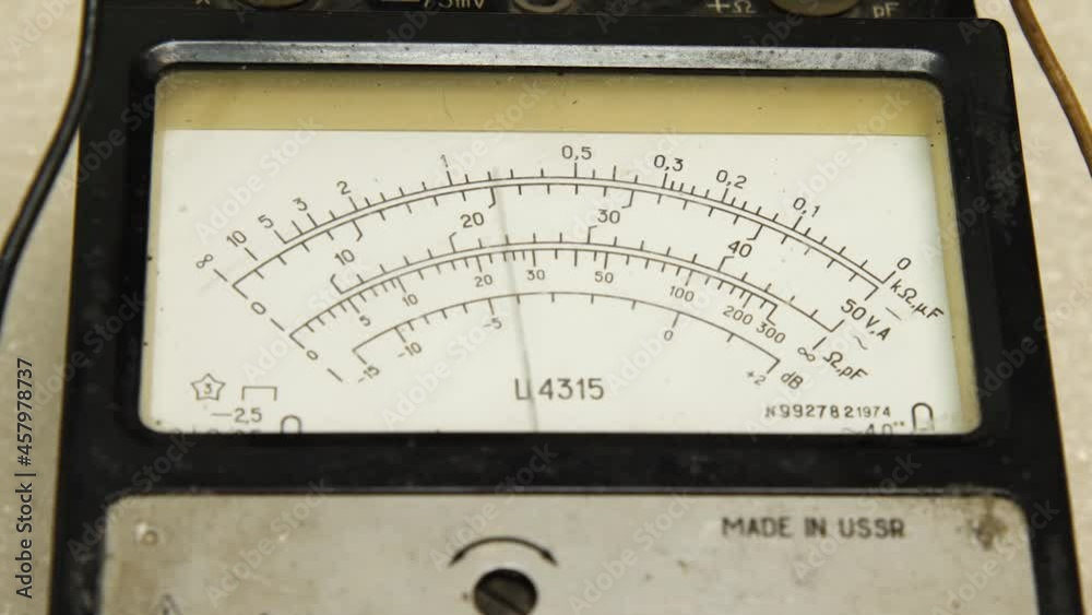 The hand runs on the dial of an old analog multimeter. The device is ...