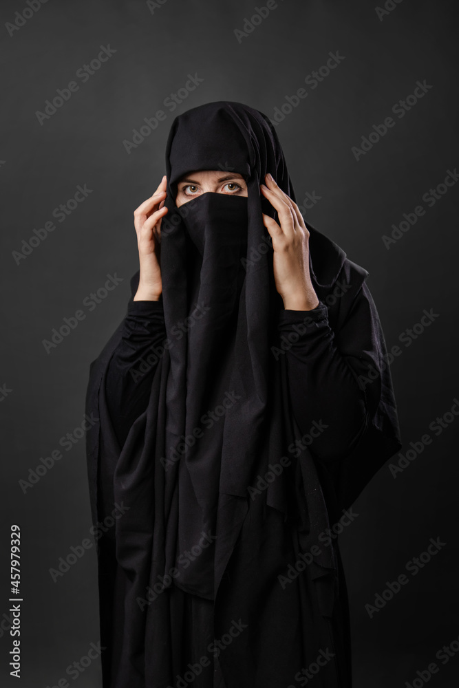 Portrait of a young, adult woman in a black burqa with a hidden face ...
