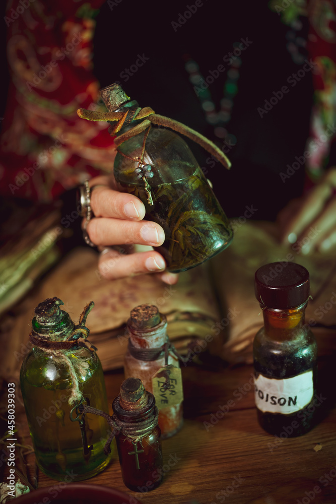 Female witch making potion on dark background, magic bottles with ...