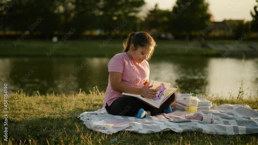 Young teenage girl student studying in nature in the park on the lawn ...