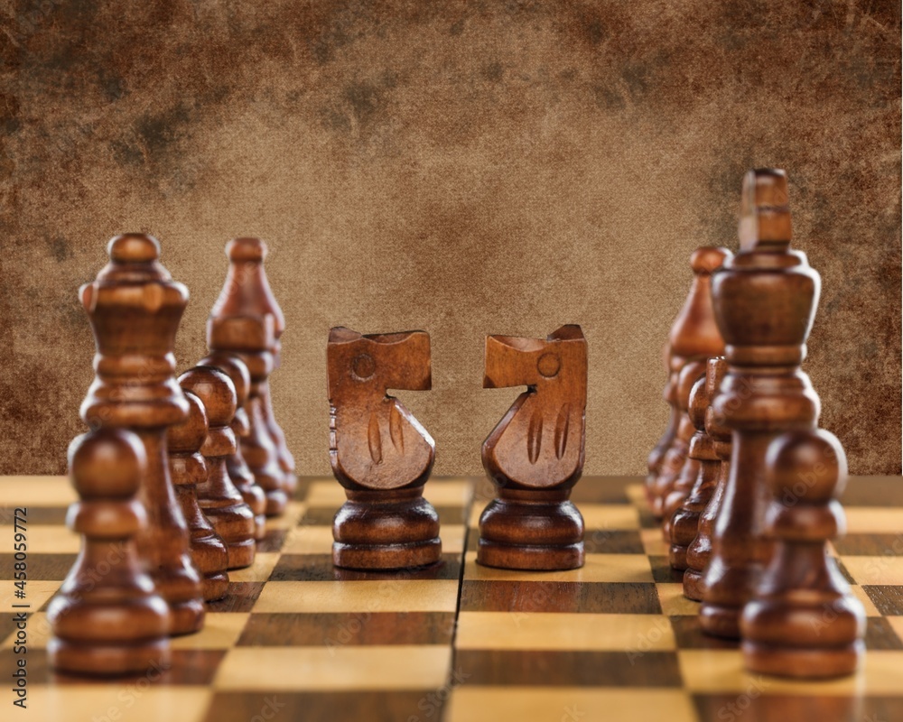 Wooden chess pieces facing each other on a vintage chessboard. Rivalry ...