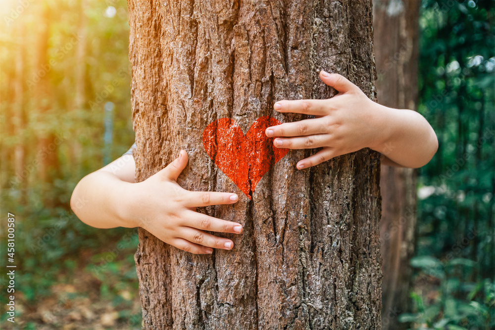 Tree embracing, a young girl hugging a tree with a red heart as a symbol of love for nature ...